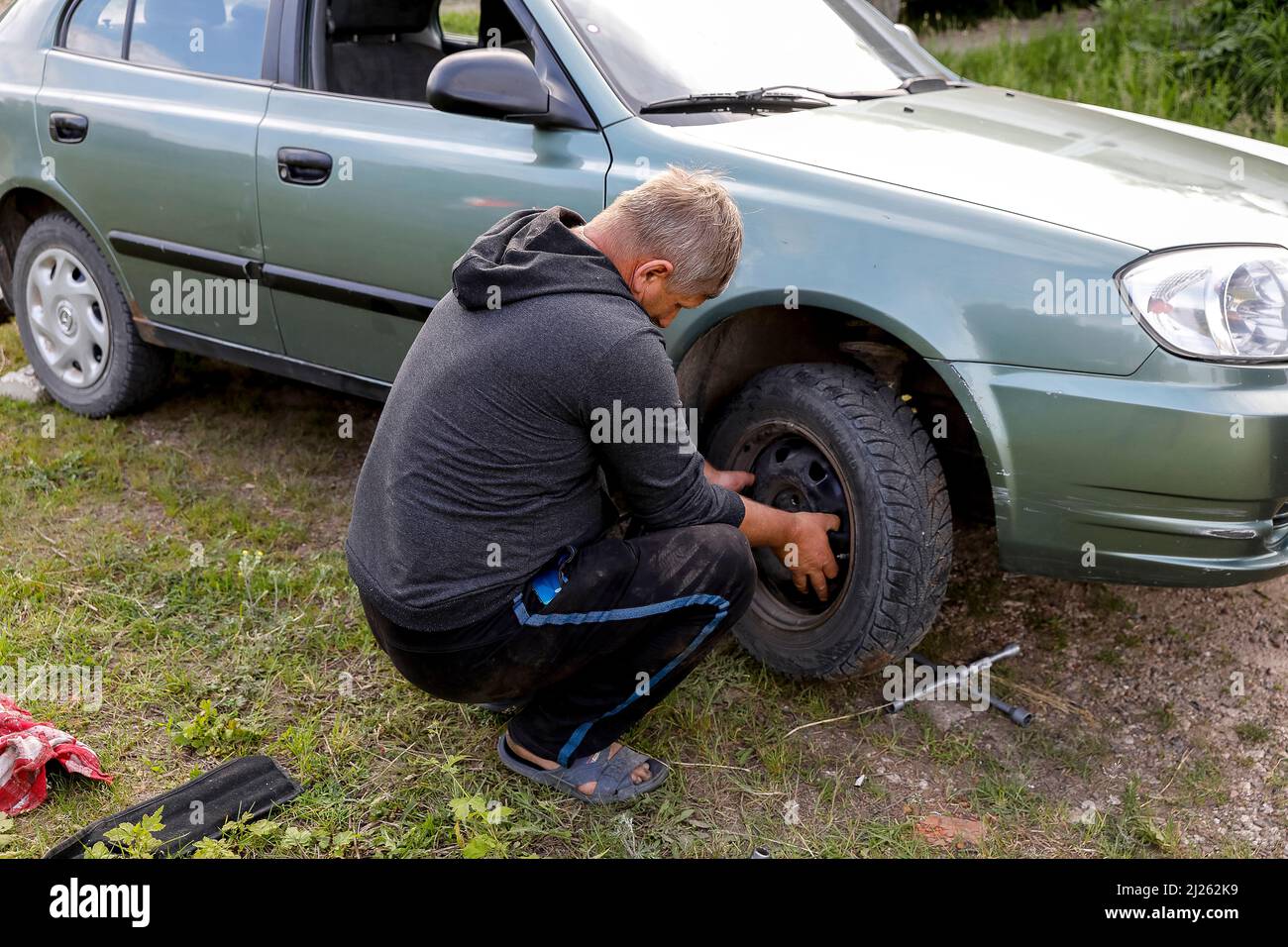 Man changing a tyre after a breakdown in a village near Soroca, Moldova ...
