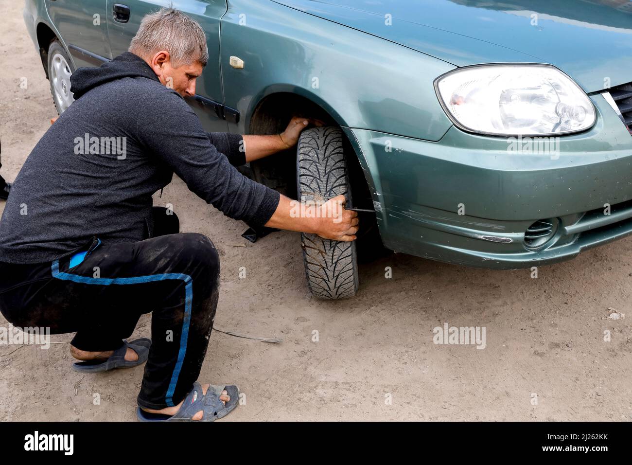 Man changing a tyre after a breakdown in a village near Soroca, Moldova ...