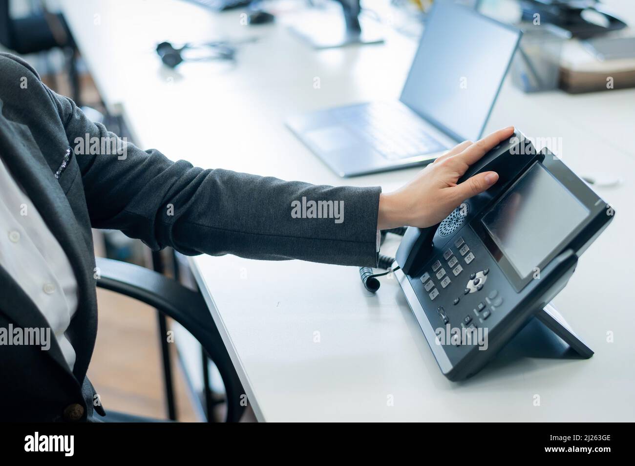 Closeup female hand on landline phone in office. Faceless woman in a ...