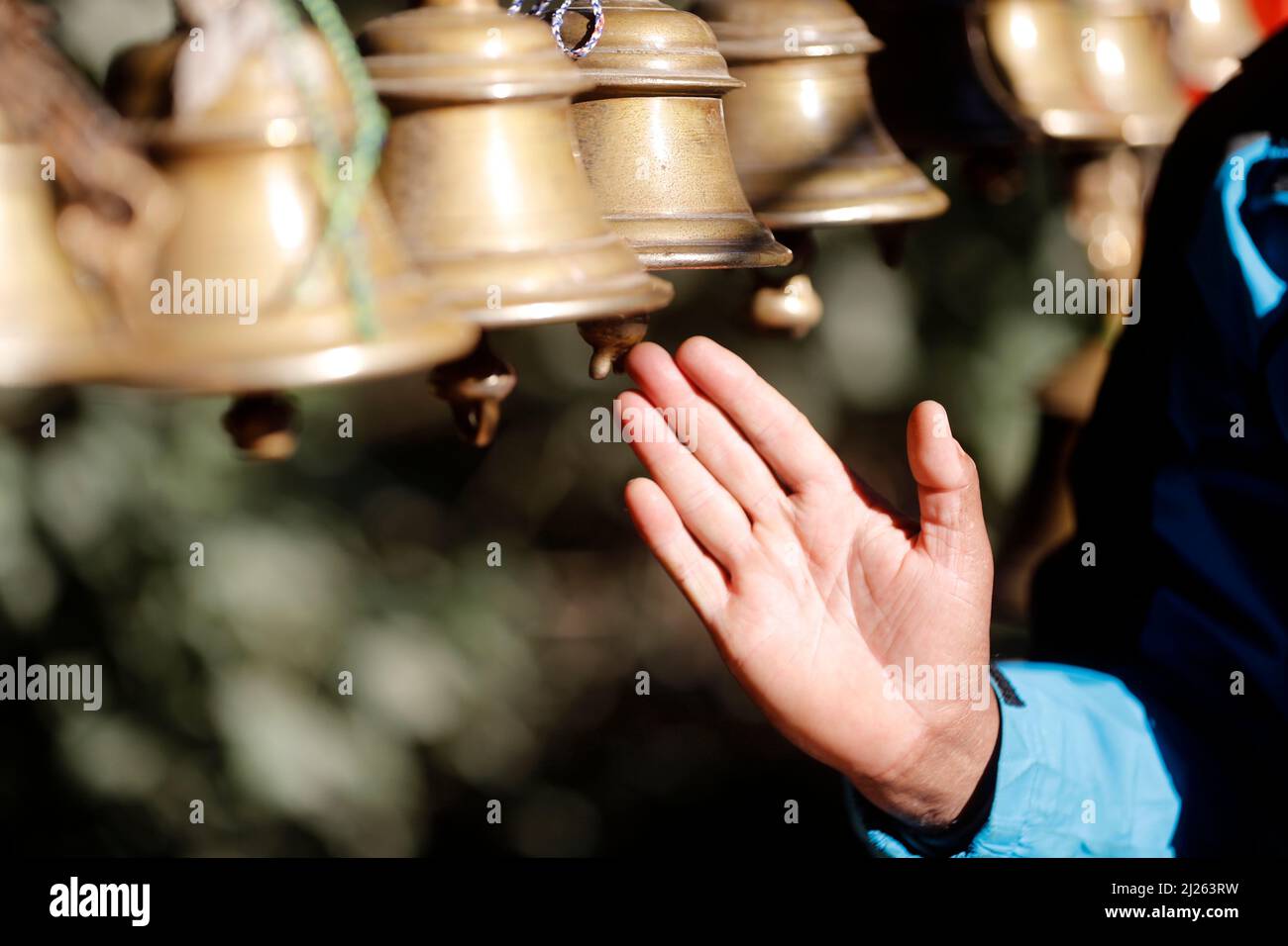 Hand of a nepali man ringing a sacred bell in a Kathmandu temple ...