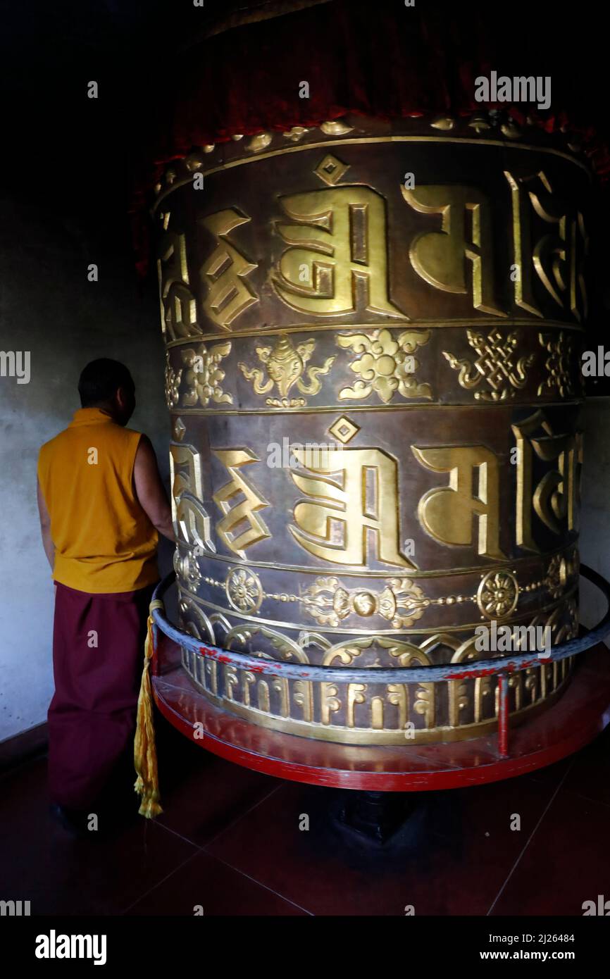 Pema Osel Ling Monastery. Tibetan monk spinning a big prayer wheel ...