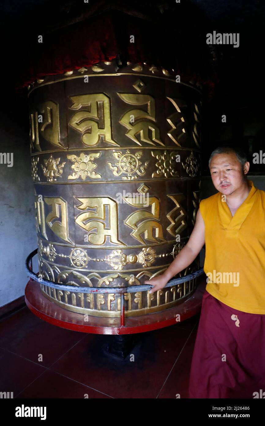 Pema Osel Ling Monastery. Tibetan monk spinning a big prayer wheel ...