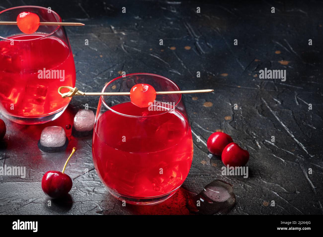 Cocktails with cherries. Alcohol drinks on a black slate background ...