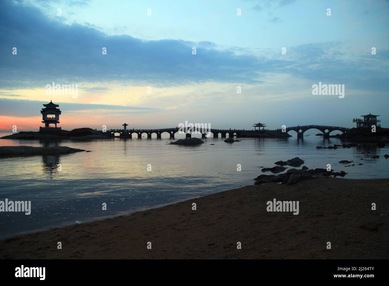 A beautiful scenery of the bridge at the beach during sunset in ...