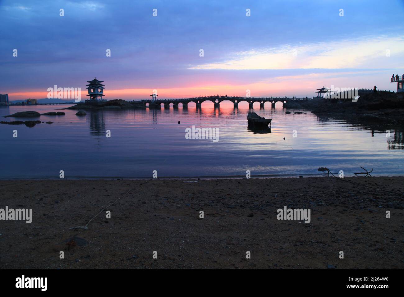 A beautiful scenery of the bridge at the beach during sunset in ...