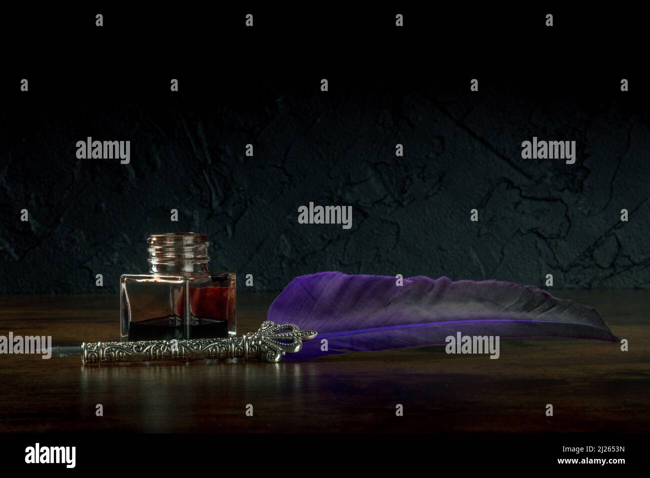 A quill pen with an old inkwell, side view on a black background with a ...