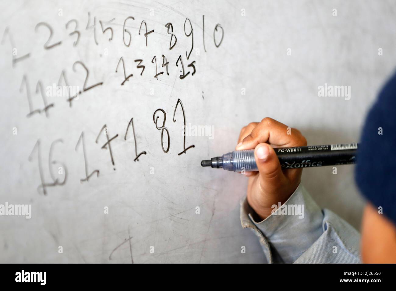 Primary school. Boy in classroom writing numbers Stock Photo - Alamy