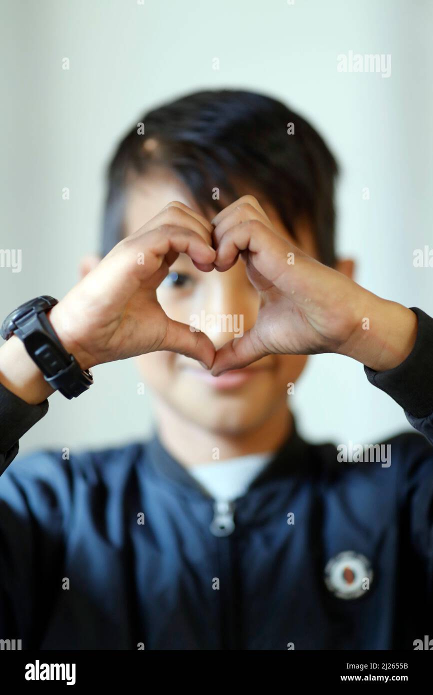 Primary school. Portrait of pupil. Boy making hands gesture love or ...