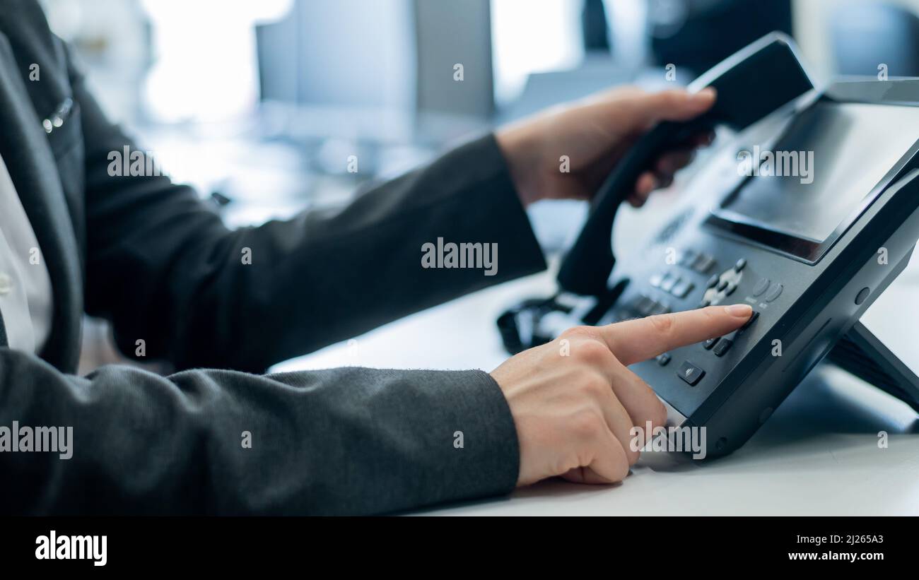 Closeup female hand on landline phone in office. Faceless woman in a ...