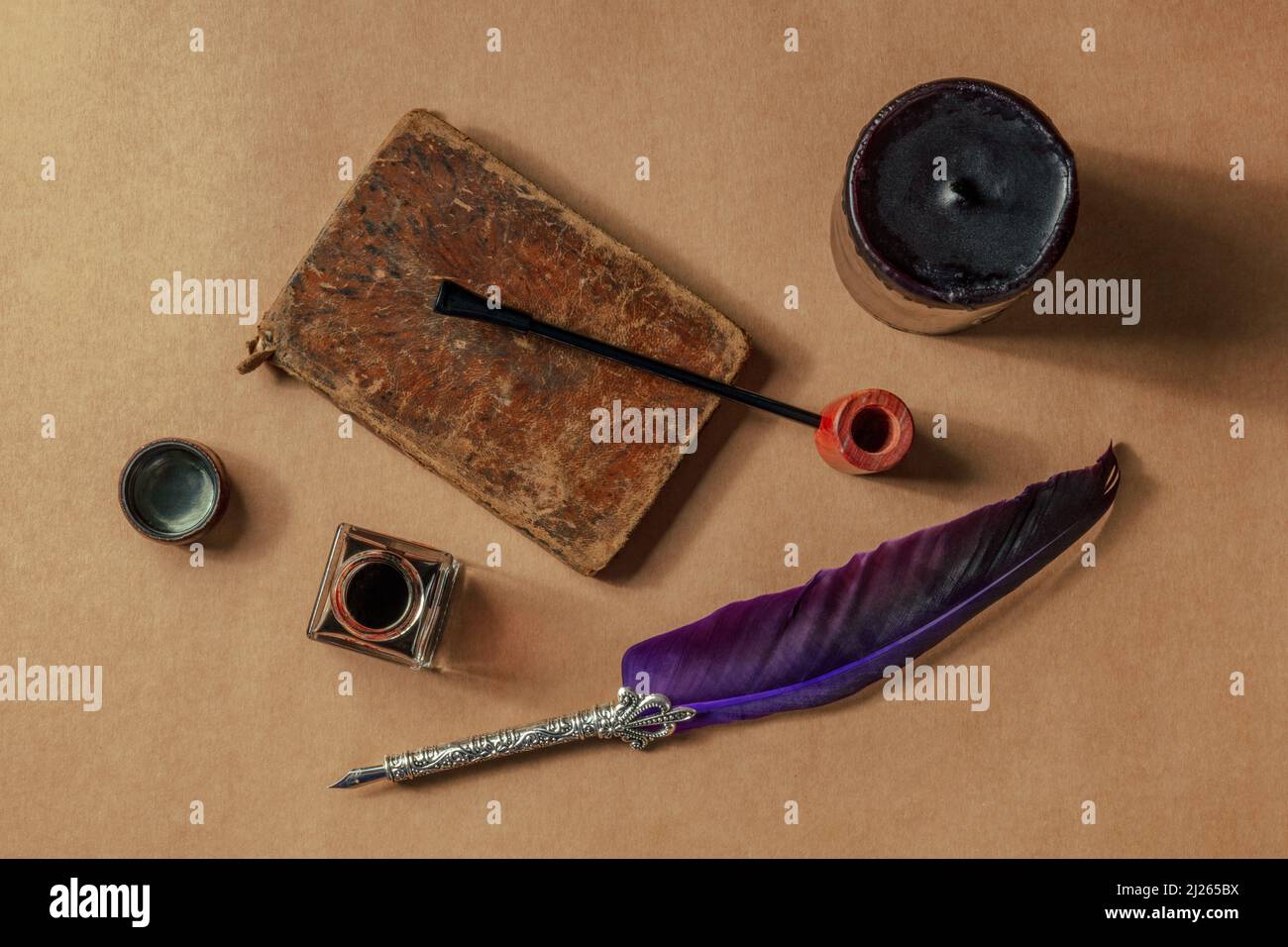 Vintage pipe, quill pen, old notebook, and a candle, shot from the top ...