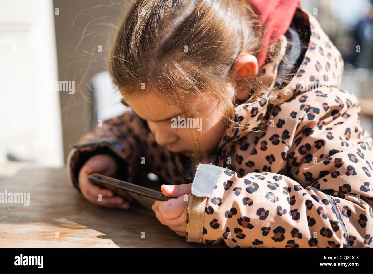Preschool child watching cartoons outdoors very close tot the eyes ...