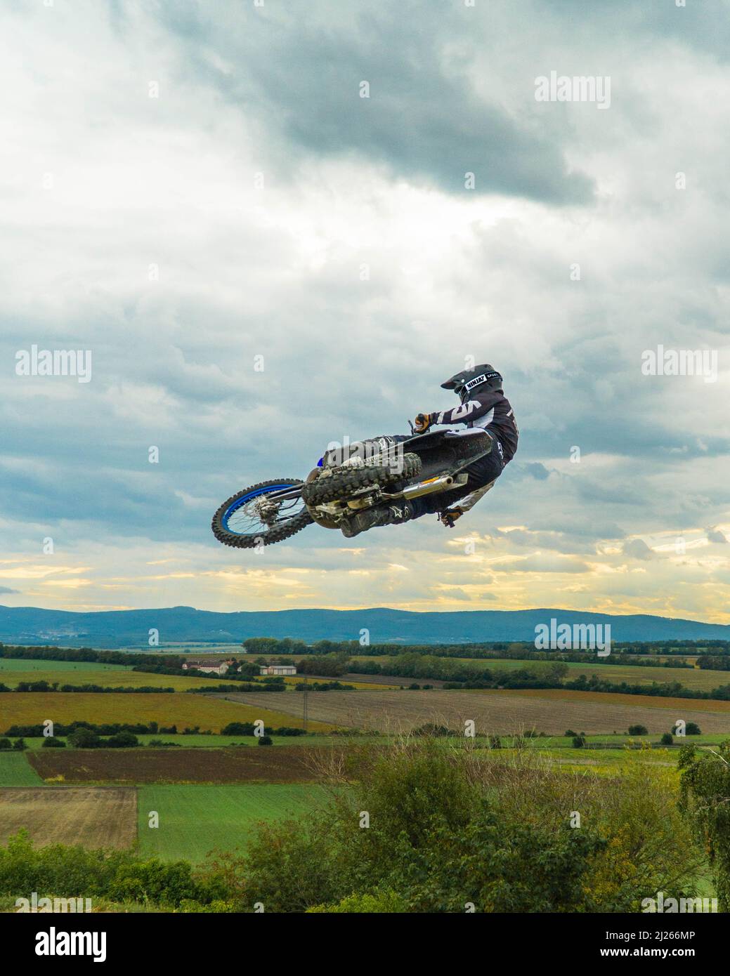A vertical shot of a motorcycle jumping over a ramp against a blue sky ...