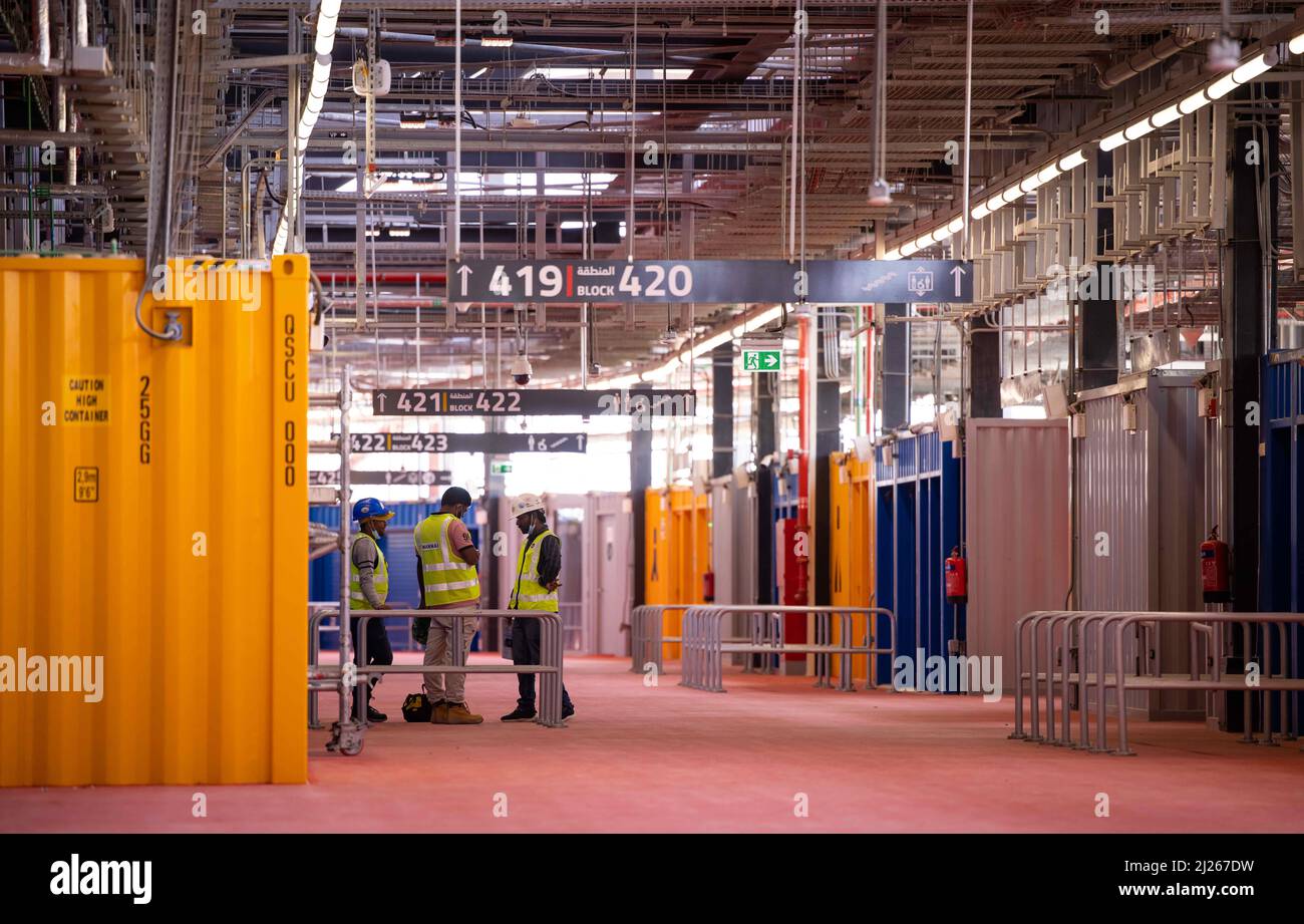 30 March 2022, Qatar, Doha: Workers stand in a hallway at Stadium 974 ...