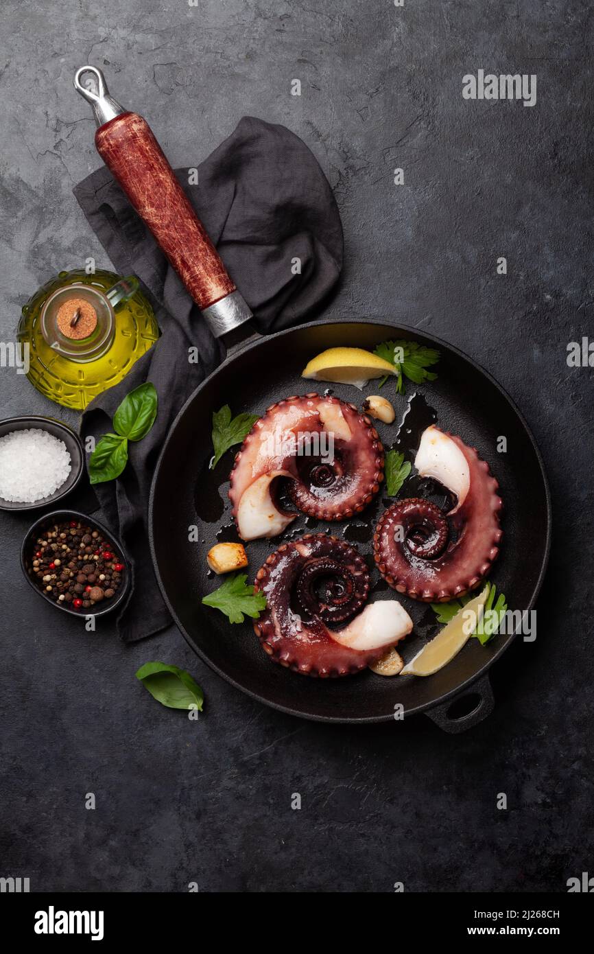 Grilled octopus with herbs and spices on frying pan. Top view flat lay ...