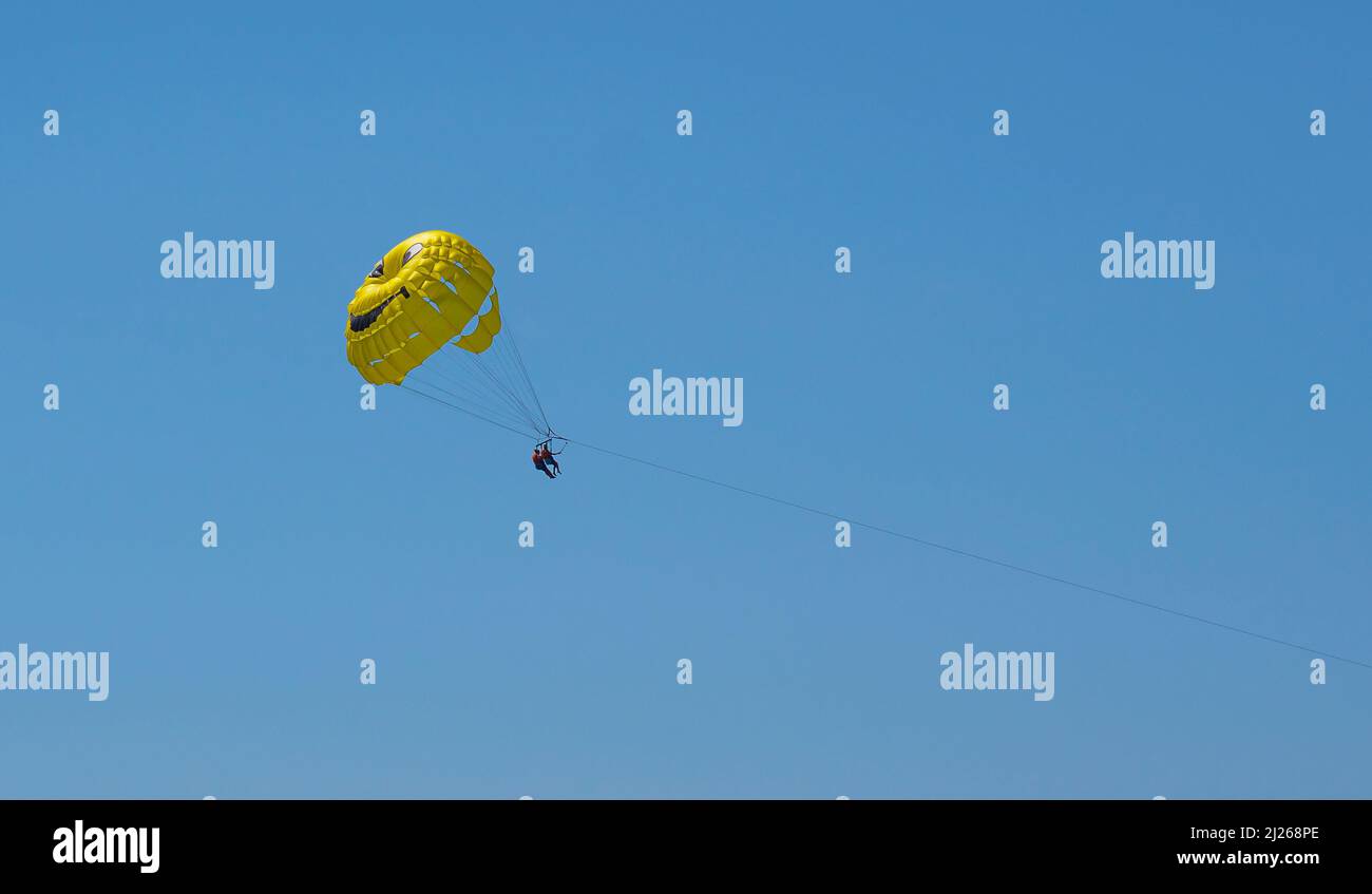 Yellow parachute in the blue sky over the sea. Parasailing extreme ...