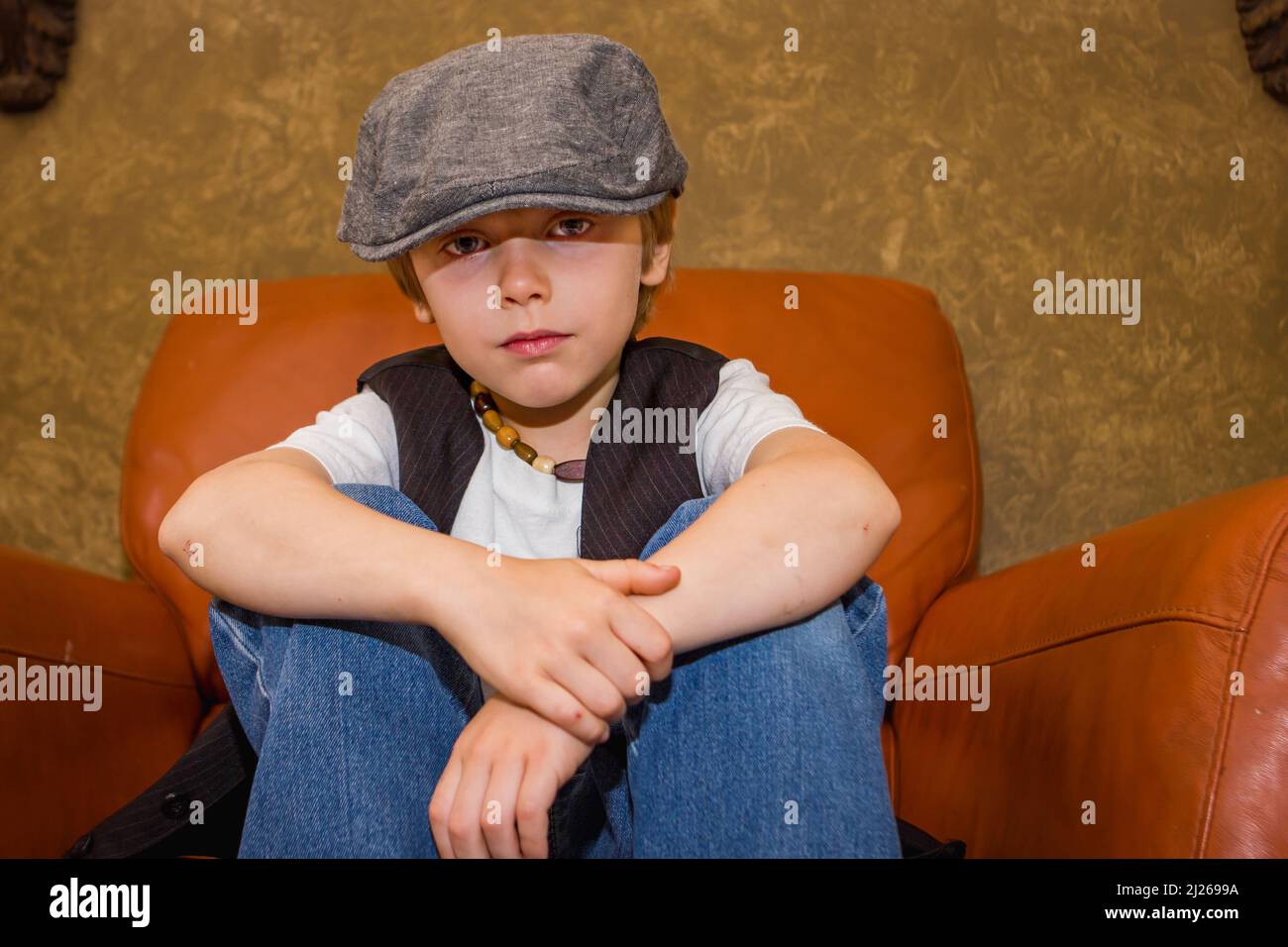 A portrait of a child male with a sad face expression sitting on an ...