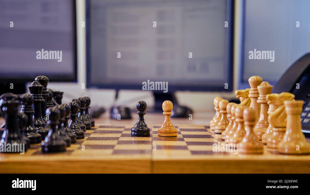 A chessboard with chess pieces placed on an office table near computer ...