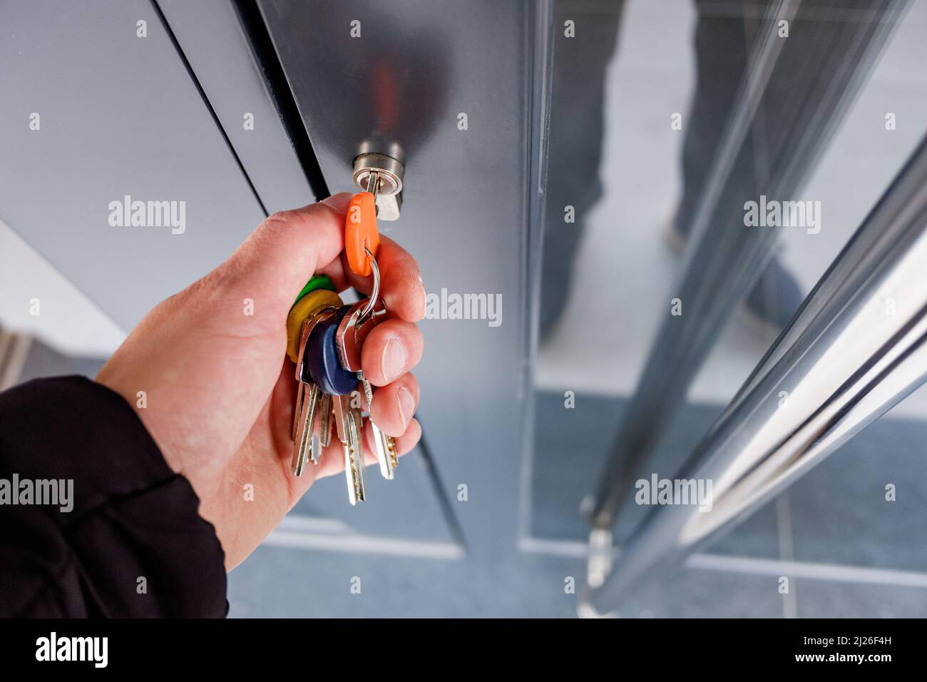 Male hand puts the key in the keyhole of the entrance door to the ...