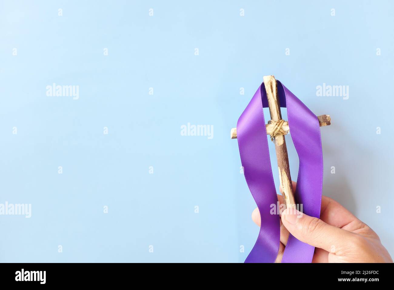 Top view of hand holding wooden cross crucifix with violet purple ...