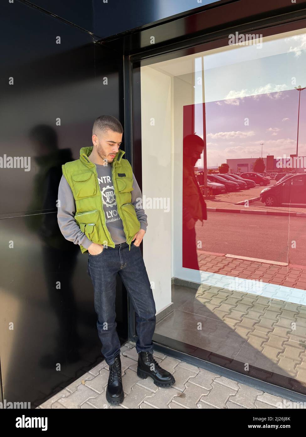 Handsome young man model in green gilet and black boots posing next to ...