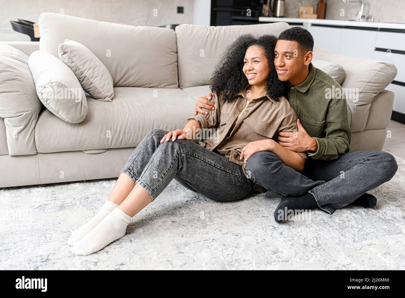 Smiling man hugging from behind his charming woman, while sitting and ...