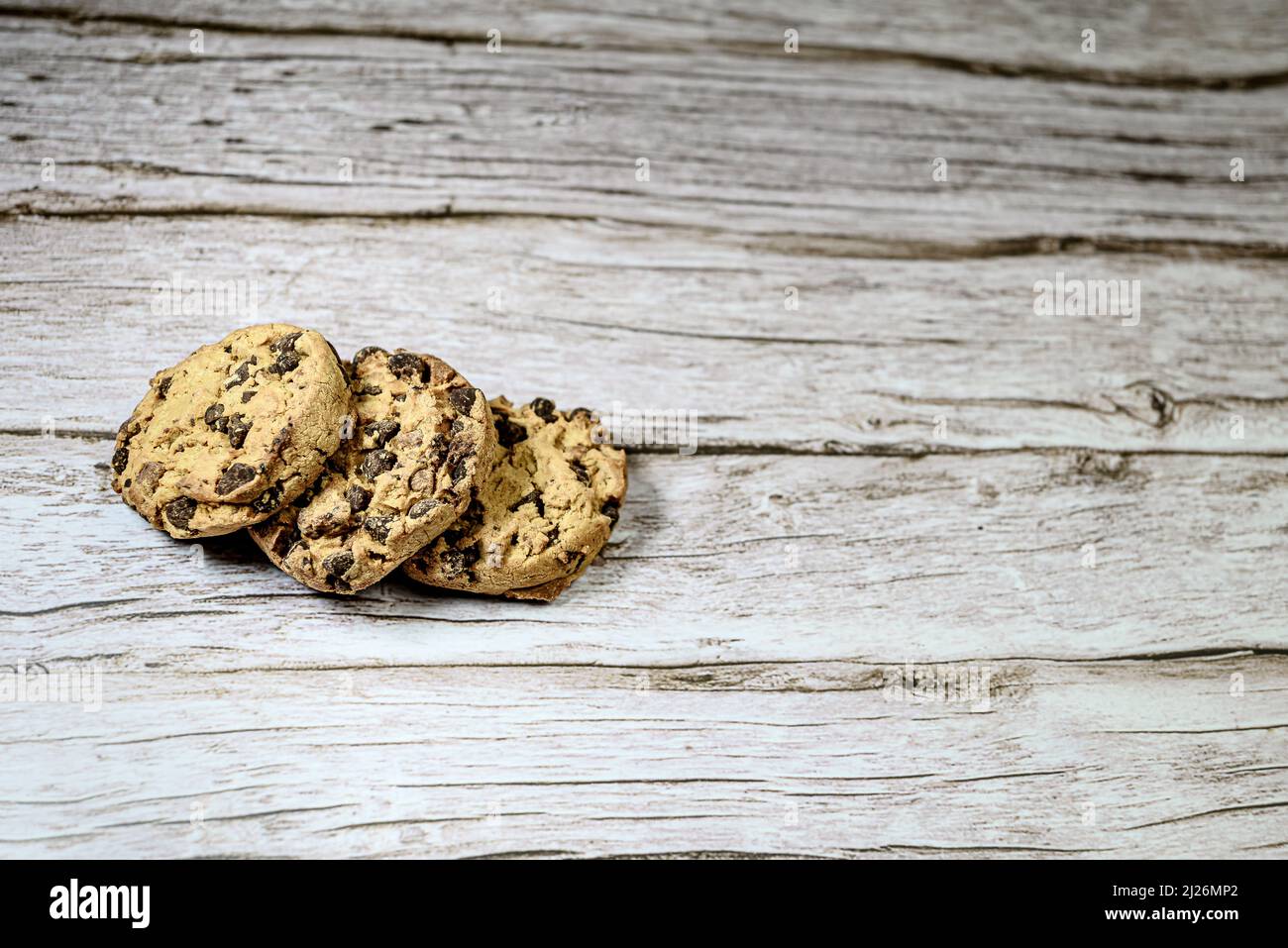 Three chocolate chip cookies isolated on rustic wooden table. Cookies ...
