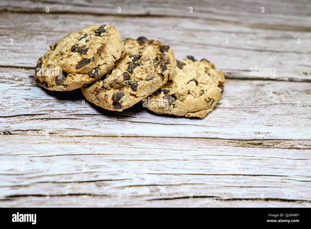 Three chocolate chip cookies isolated on rustic wooden table. Cookies ...
