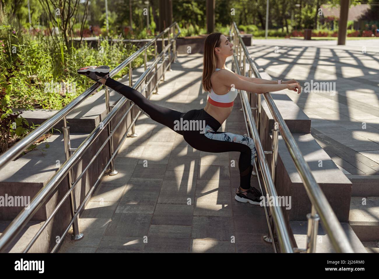 Beautiful lady does stretching exercise on ramp with metal railings in ...