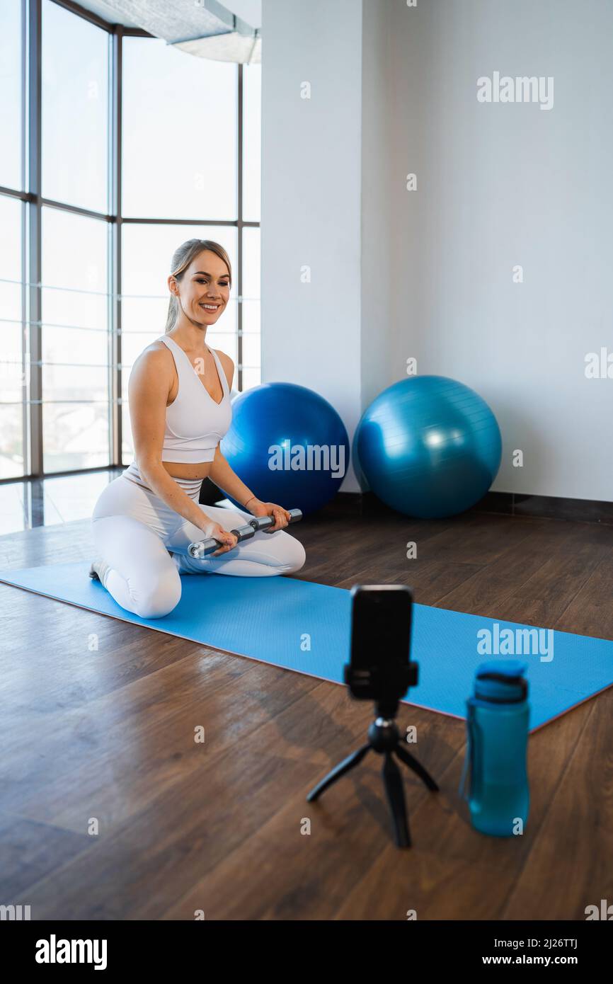 Female fitness streamer with dumbbells recording video broadcast on ...