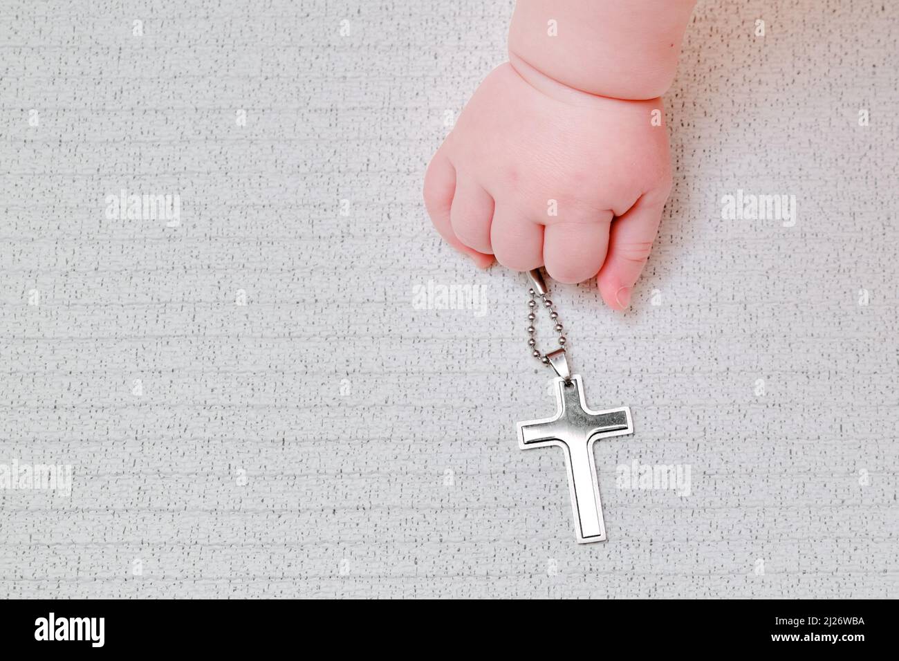 Baby hand and christian religious symbol of the cross, close-up ...