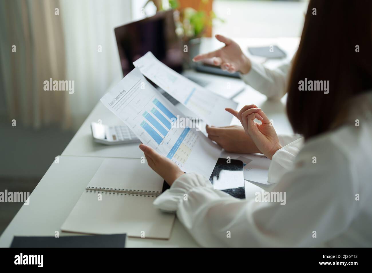 Two colleagues discussing paperwork financial report graph data on ...