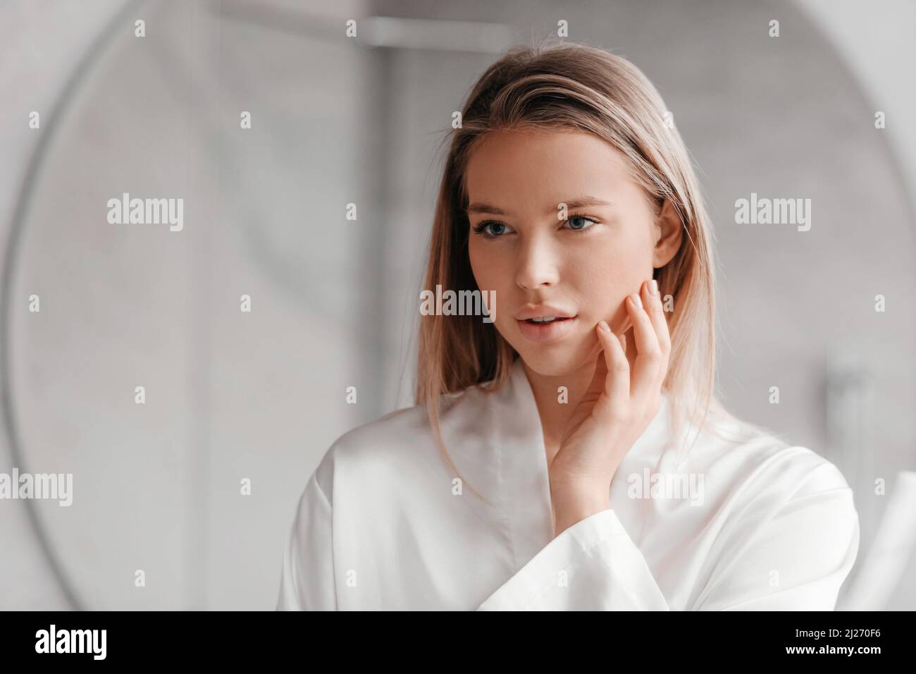 Natural beauty. Attractive lady looking at her reflection in mirror and ...