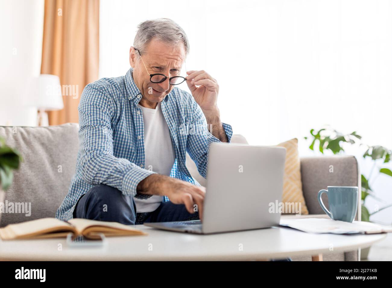 Mature man squinting using laptop, looking at pc screen Stock Photo - Alamy