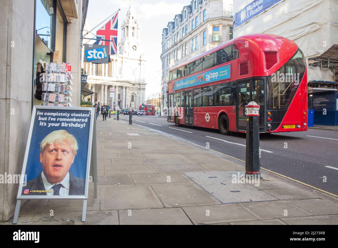A double-decker bus runs past a signboard featuring Britain's Prime ...