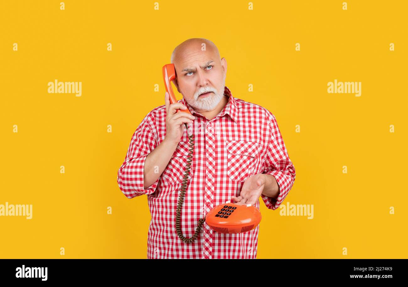 serious old man with retro telephone on yellow background Stock Photo ...