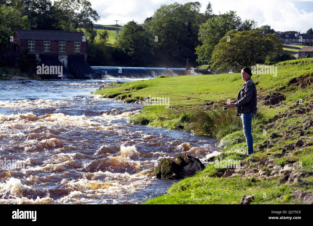 A man fishing for trout on the River Wharfe in The Yorkshire Dales near ...