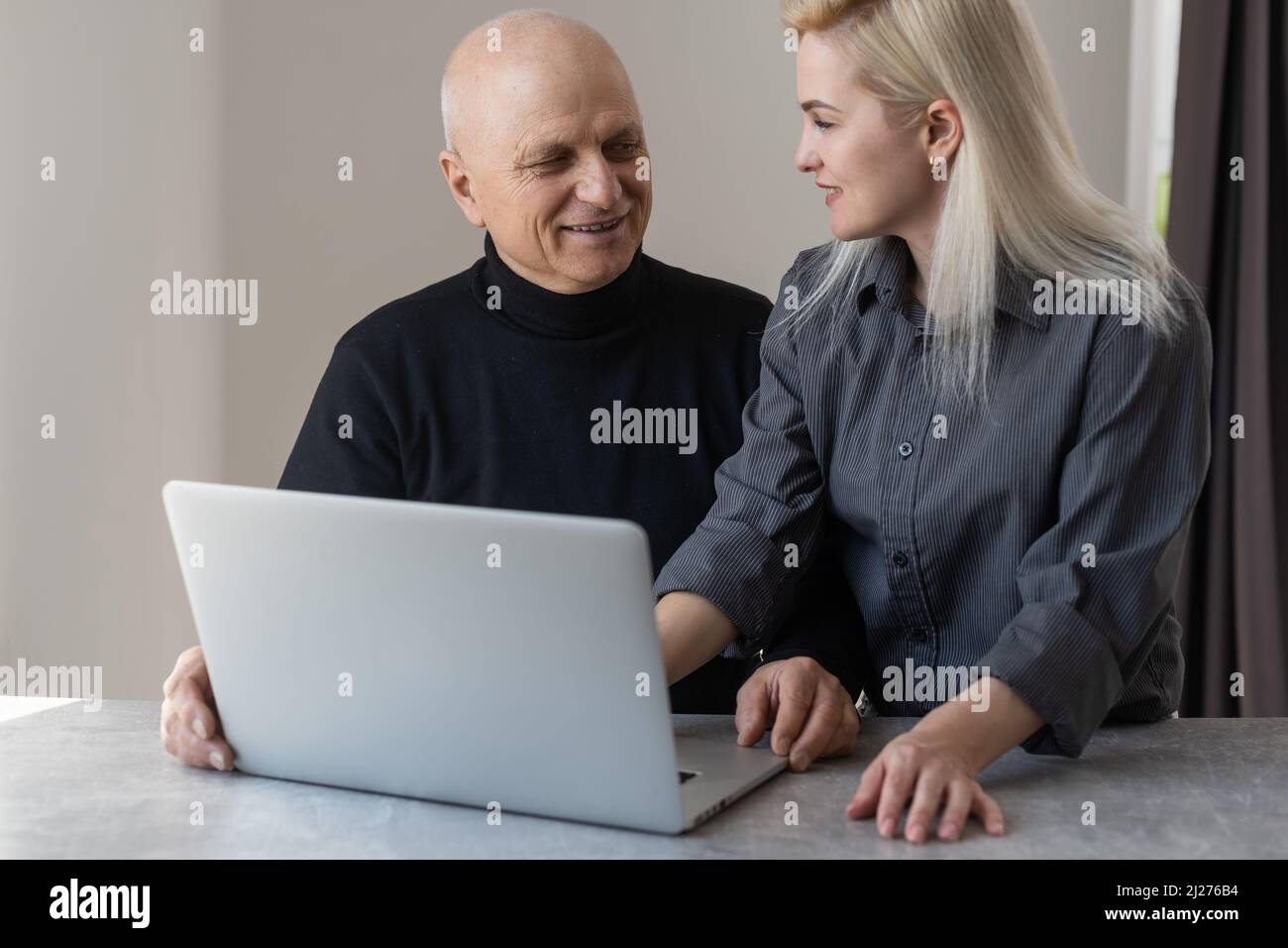 Happy smiling young girl teaching and showing new computer technology to her grandfather Stock ...