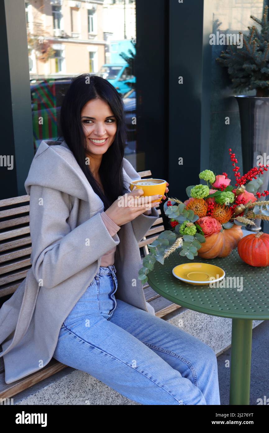 Beautiful Ukrainian young woman in casual autumn clothes drinking ...