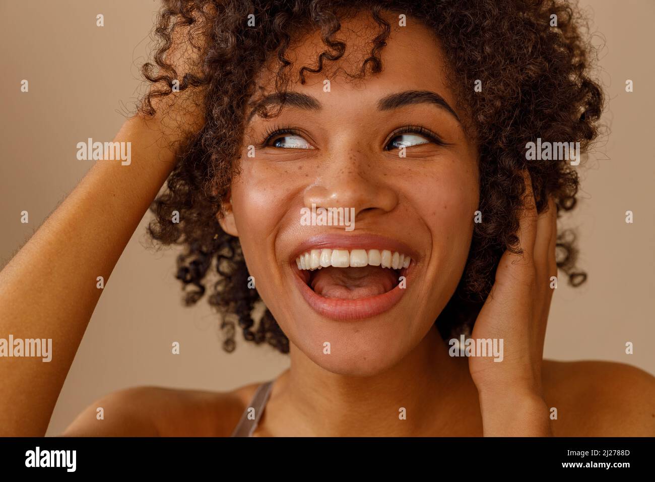Happy young woman touching clean hair in studio interior Stock Photo ...
