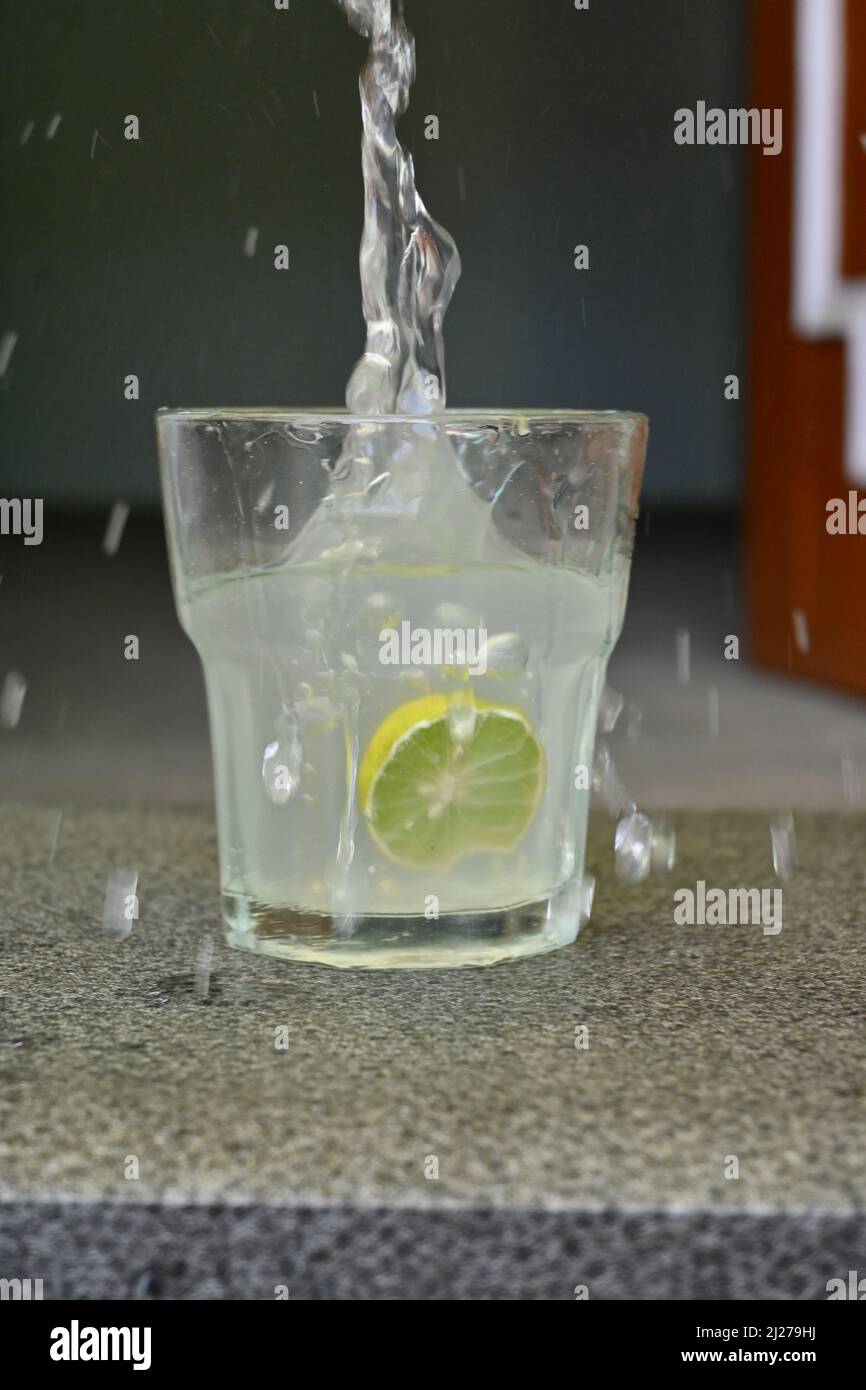 closeup the lemon juice flow in the glass over out of focus grey brown ...