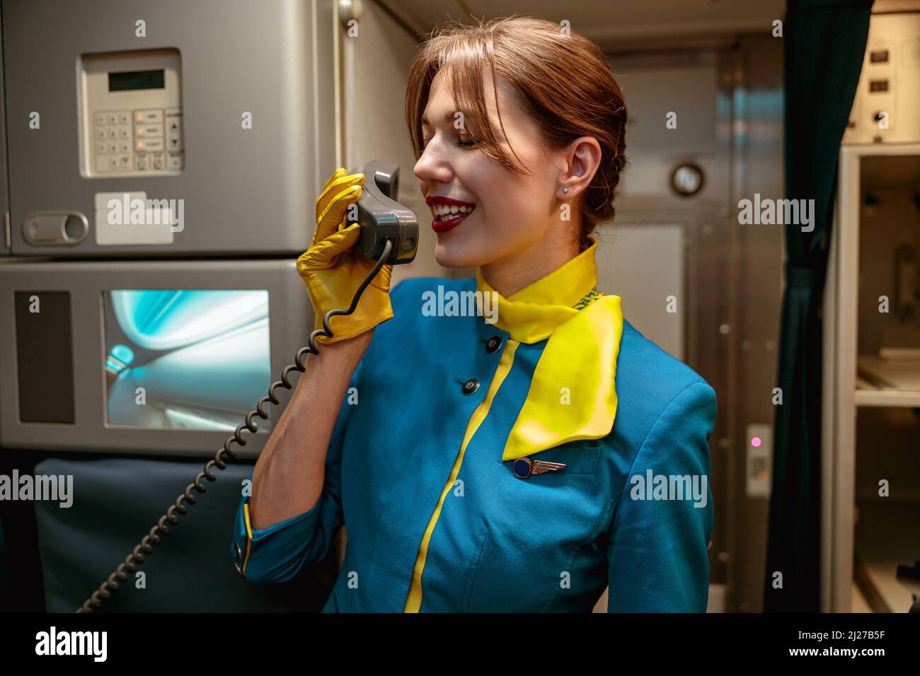Cheerful flight attendant talking on telephone in airplane Stock Photo ...