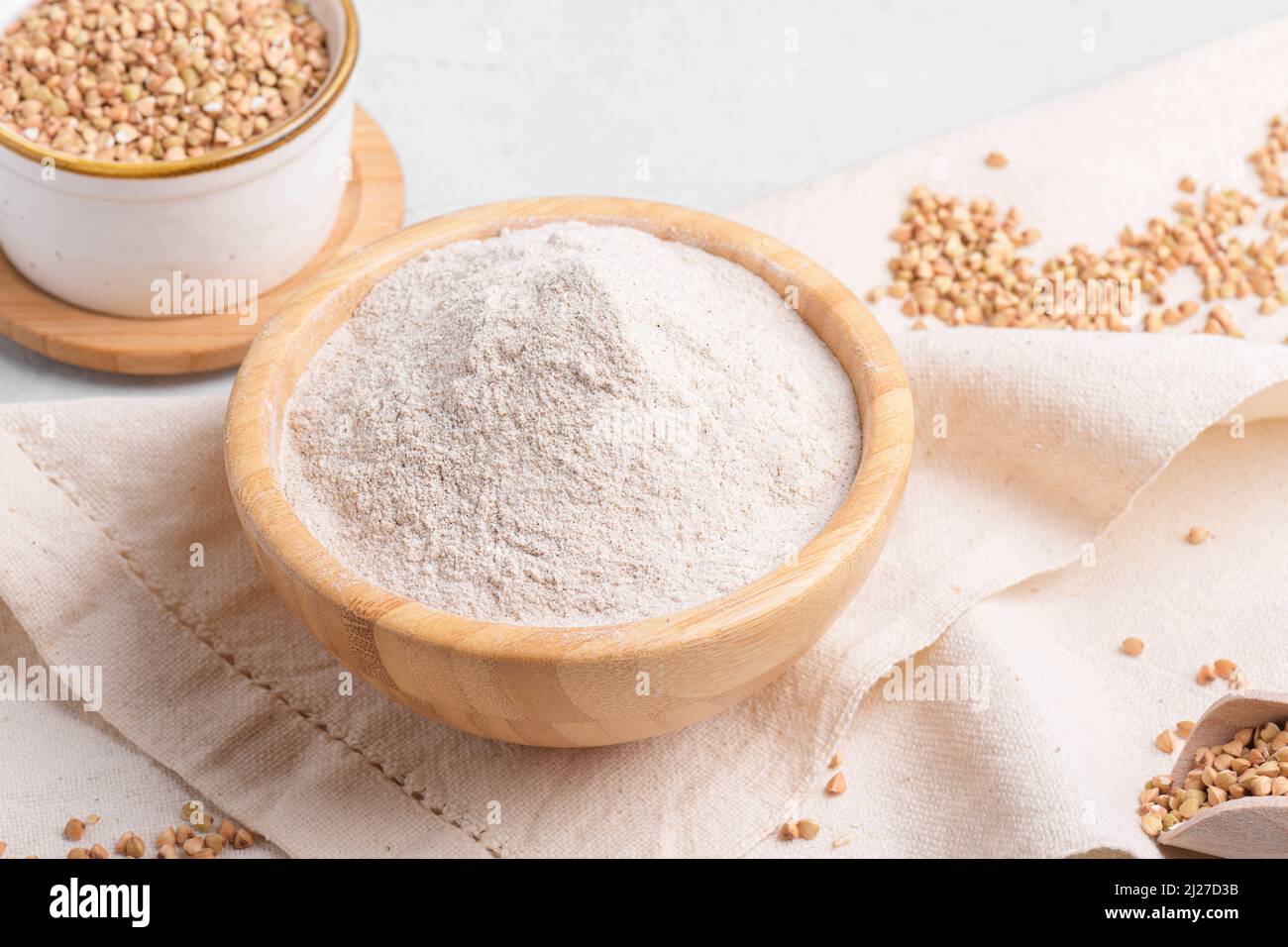 Buckwheat flour in a wooden bowl and raw green buckwheat grain on ...