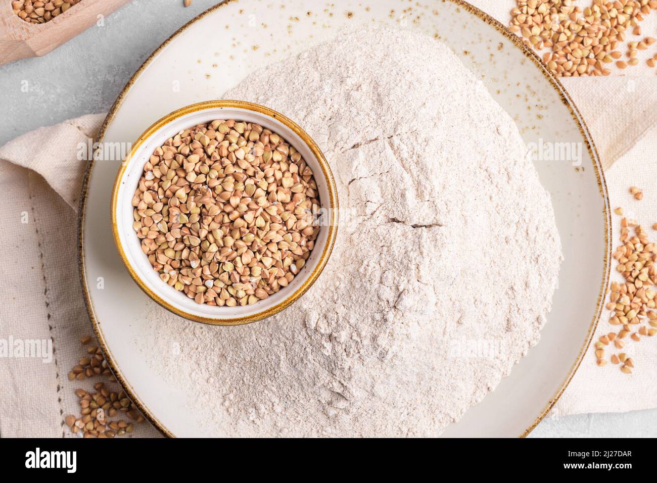 Buckwheat flour in a ceramic plate and raw green buckwheat grain on a ...