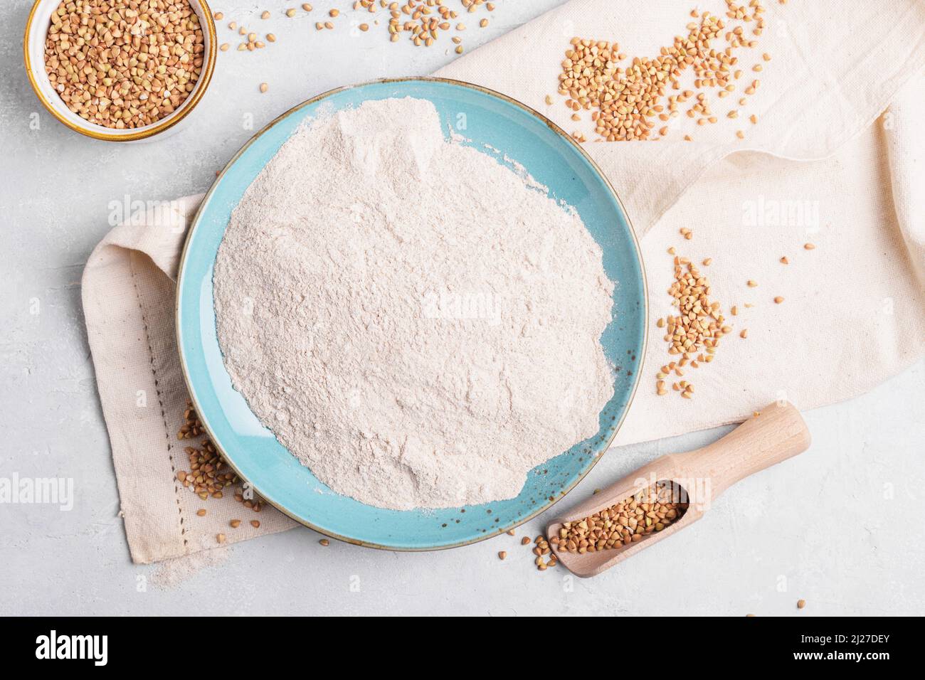 Buckwheat flour in a blu ceramic plate and raw green buckwheat grain on ...