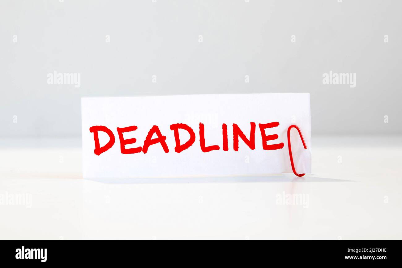 Deadline word written on a post note and hanged on the cork-board with ...