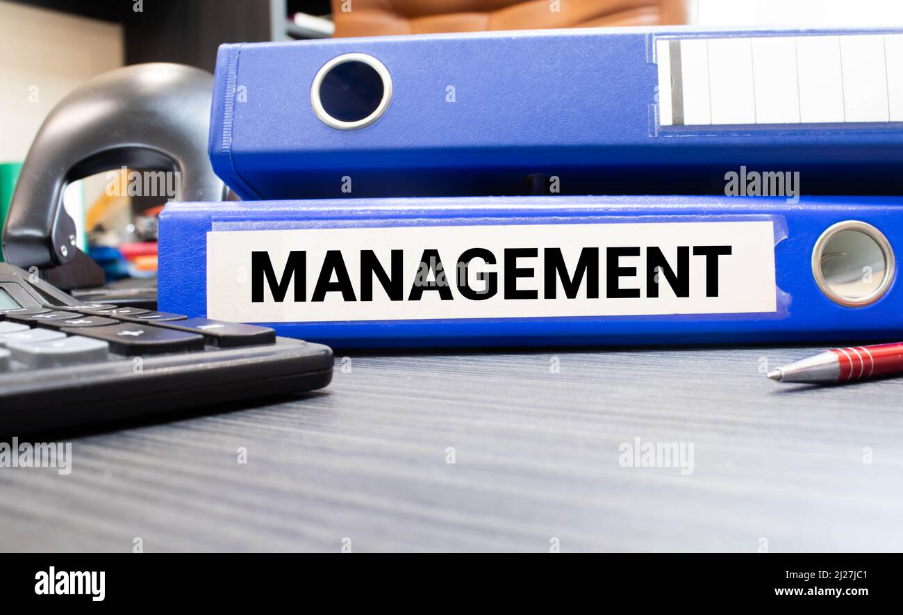 Management words on labels with document binders, graphs and business ...