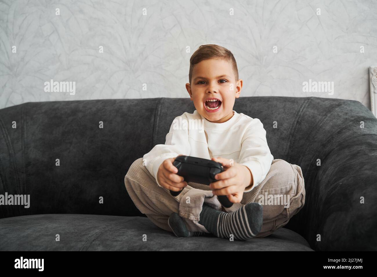 Surprised kid with gamepad playing console games at home. Gambling ...