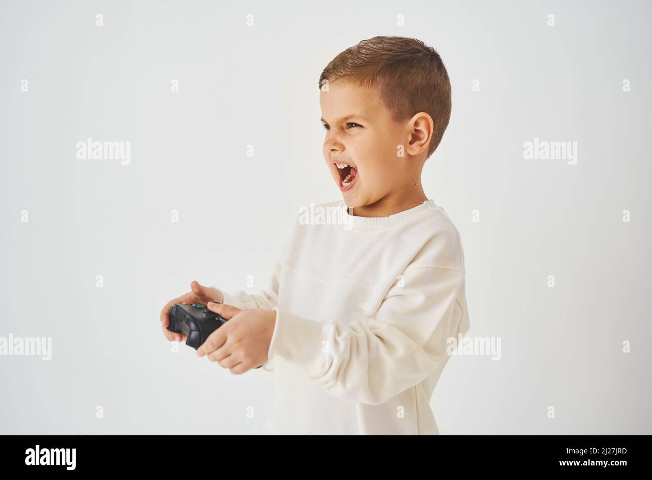 Emotional child with gamepad on white background. Boy is playing games ...