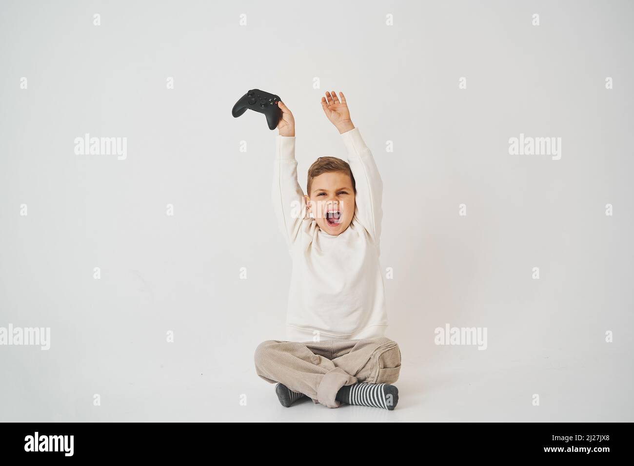 Happy boy with a gamepad raises his hands up and shouts. The emotional ...
