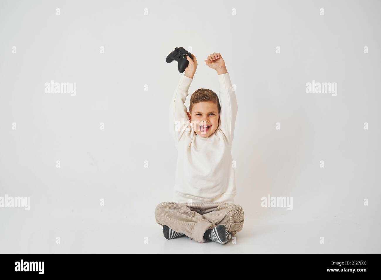 Happy boy with a gamepad raises his hands up and shouts. The emotional ...